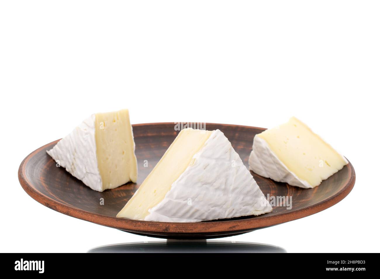 Three fragrant pieces of brie cheese on a ceramic platter, close-up ...