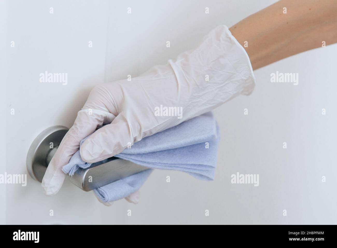 Cleaning door handle with blue wipe in white gloves. Sanitize surfaces ...