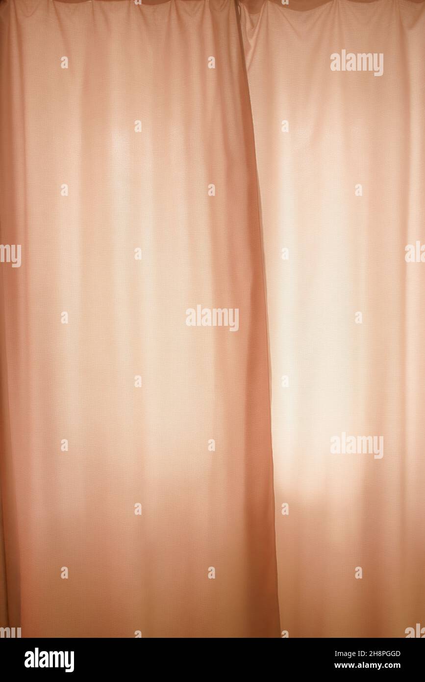 Window with closed beige curtains close up. View from the room to a ...