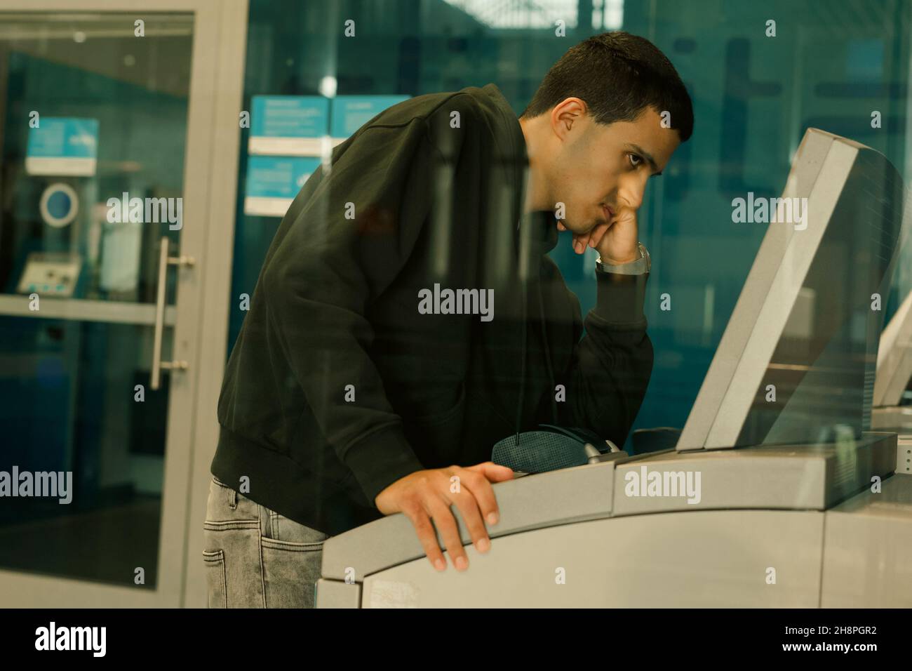Young man withdrawing money at an ATM in the city.Teenage using credit ...