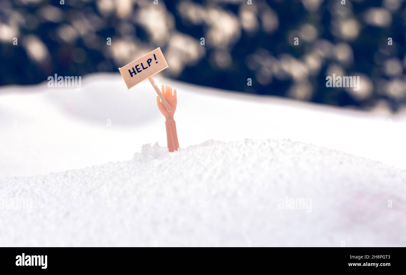 Dolls hand with a "Help" sign waving from asnowdrift Stock Photo - Alamy