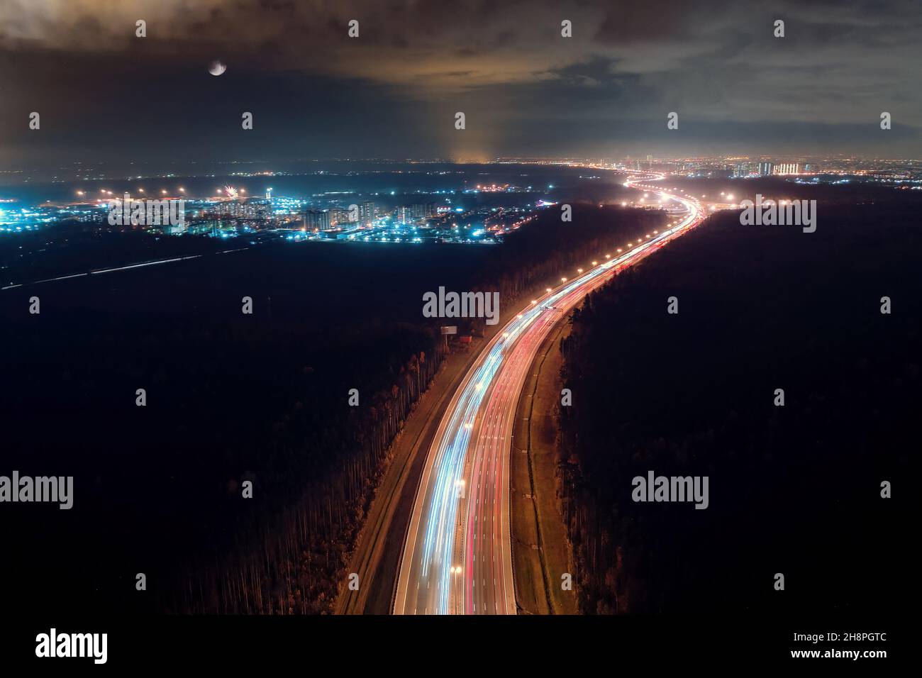 Highway road and illuminated city at night. Aerial industrial landscape ...