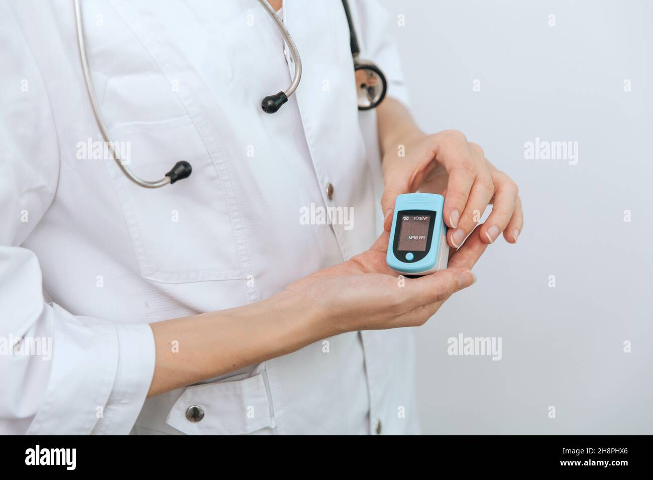 Pulse oximeter with hand of doctor isolated on white. Measuring oxygen ...