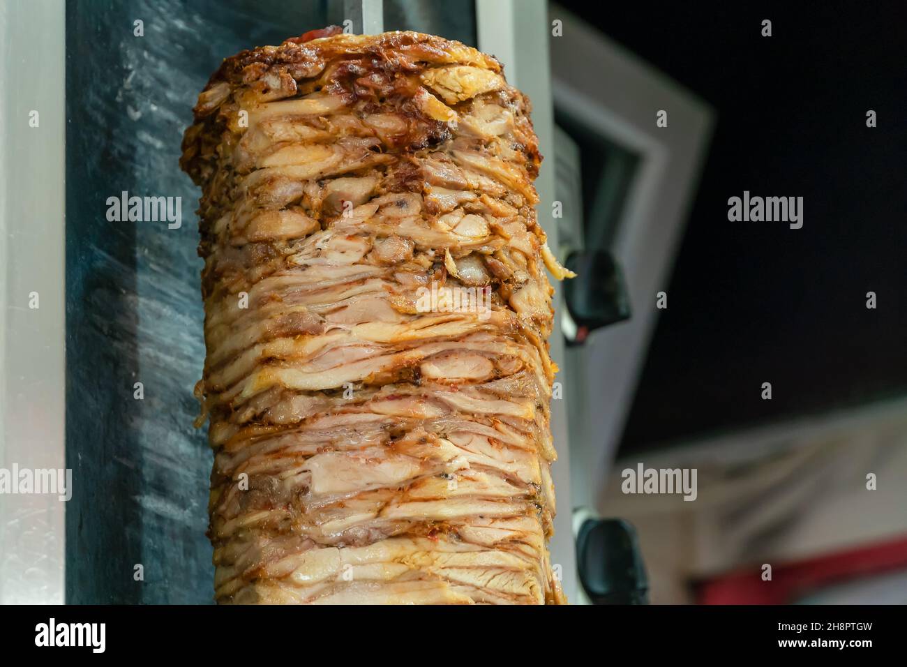 Close-up of a stainless steel machine slowly grilling layers of juicy ...