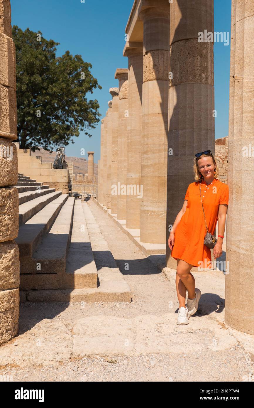 A woman stands in the ancient acropolis of Lindos against the ...