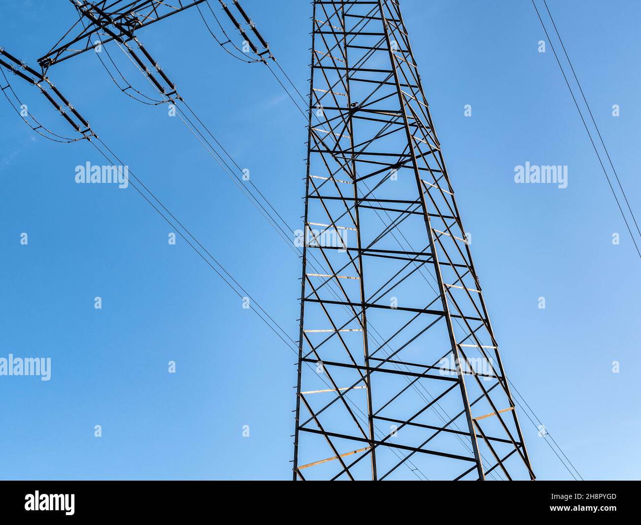 Electricity pylon in the middle from below under a blue sky Stock Photo ...