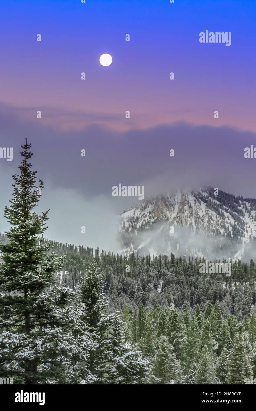 full moon setting above ross peak in the bridger mountains in winter ...