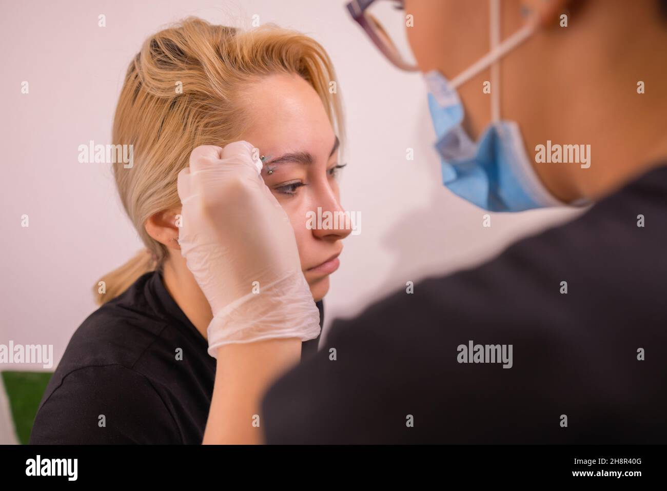Professional placing the jewel of piercing on the temple on the head ...