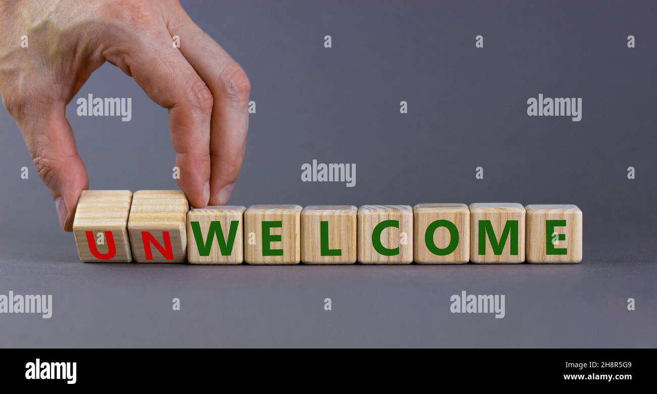 Welcome or unwelcome symbol. Businessman turns wooden cubes and changes ...