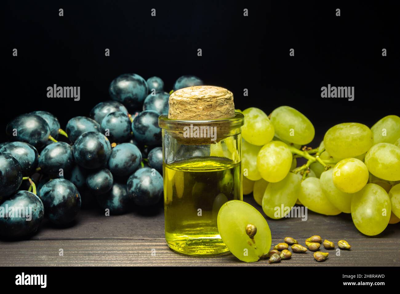 Grape oil seed in small vintage bottle. Heap of grape seeds with green ...