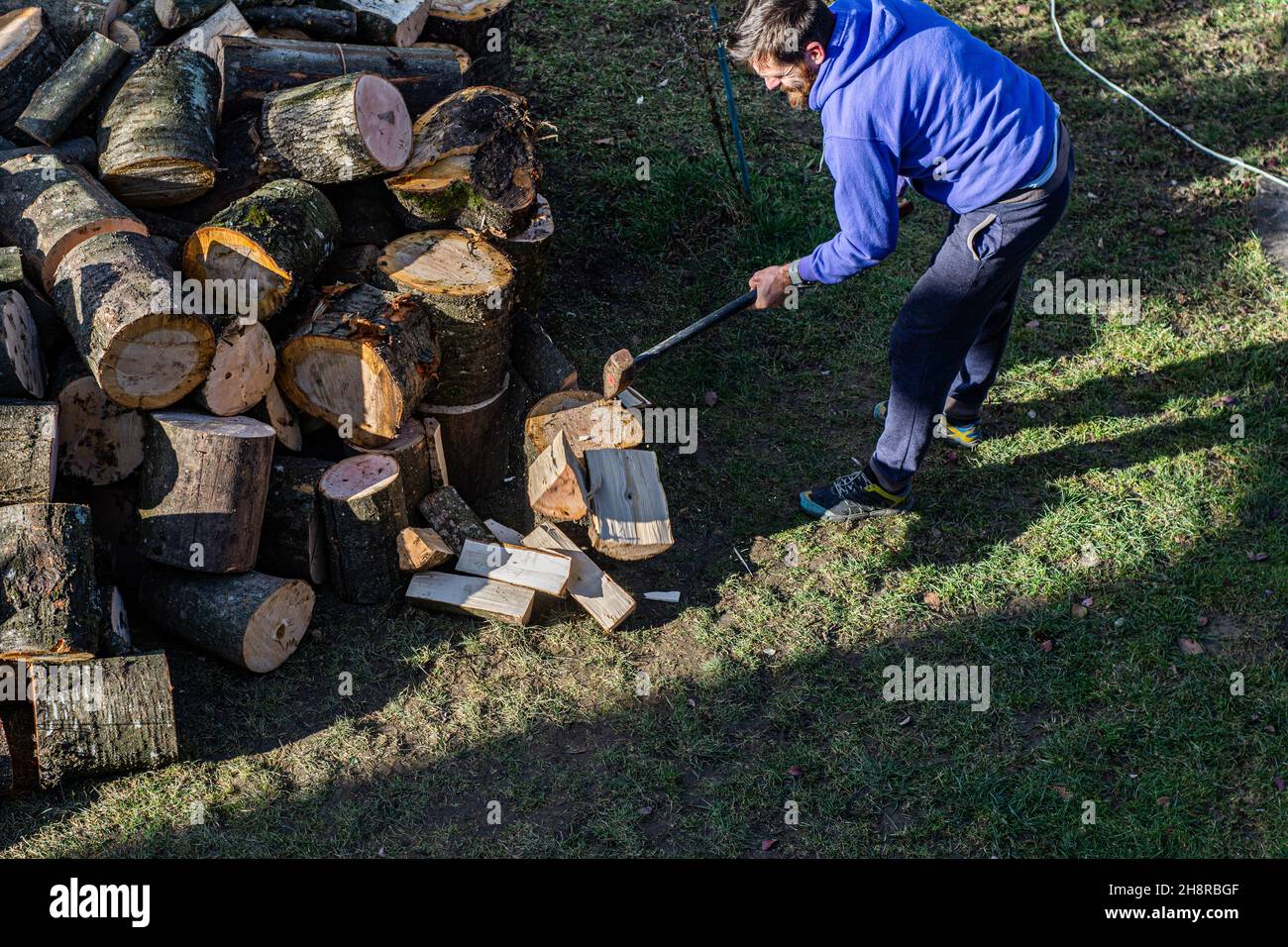 Man chopping wood with an ax in his hand. Standing by a log for ...