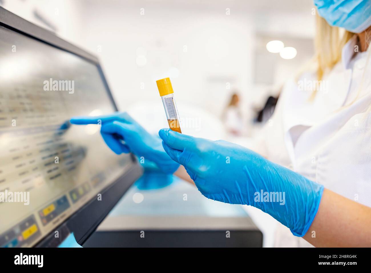 A nurse with a mask on her face and with sterile gloves is holding a ...