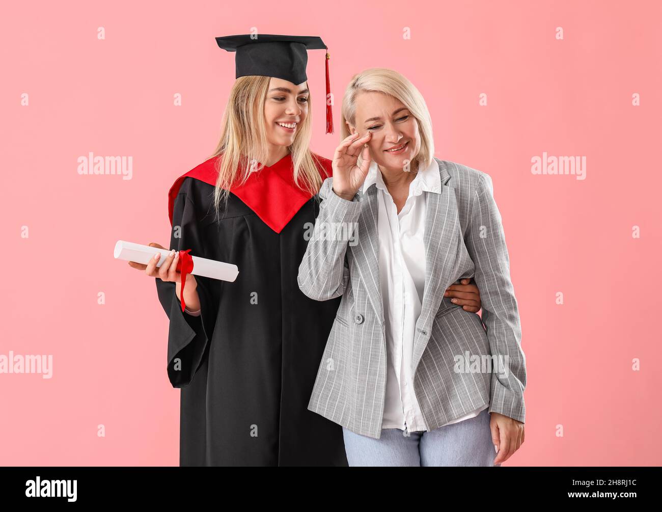 Happy female graduation student with her mother on color background ...