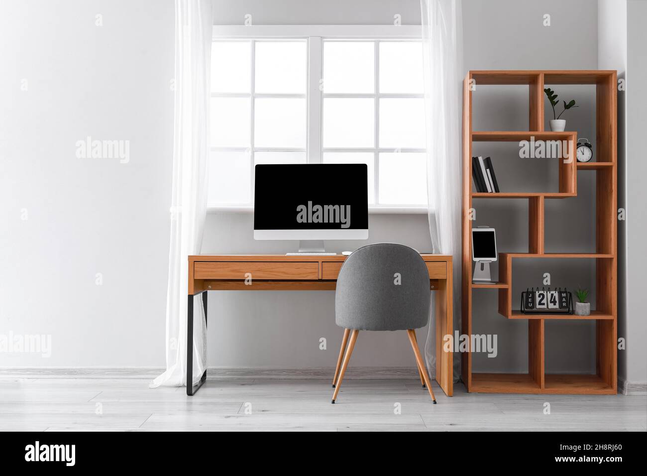 Wooden table with computer and shelving unit near window in office ...