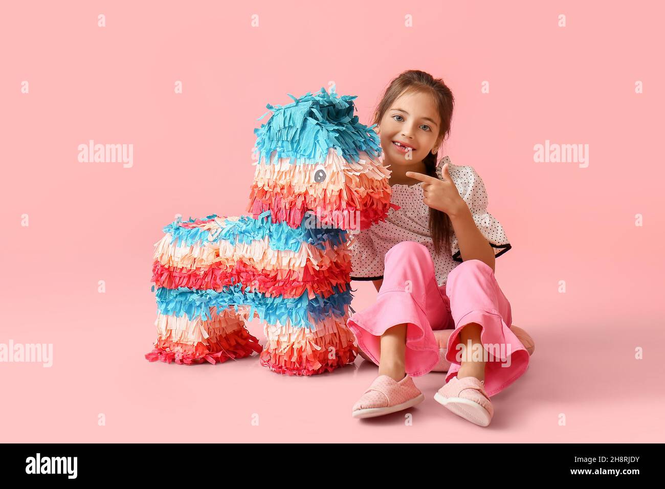 Little girl pointing at Mexican pinata on color background Stock Photo ...