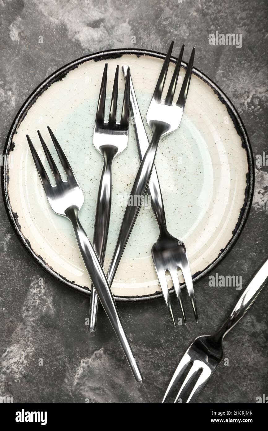 Silver forks and plate on dark table background Stock Photo - Alamy
