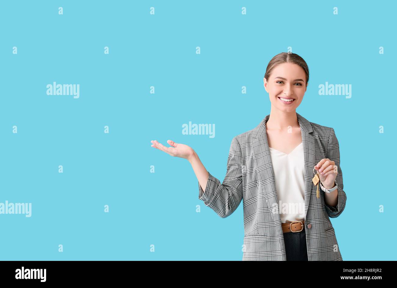 Real estate agent with key from house on blue background Stock Photo ...
