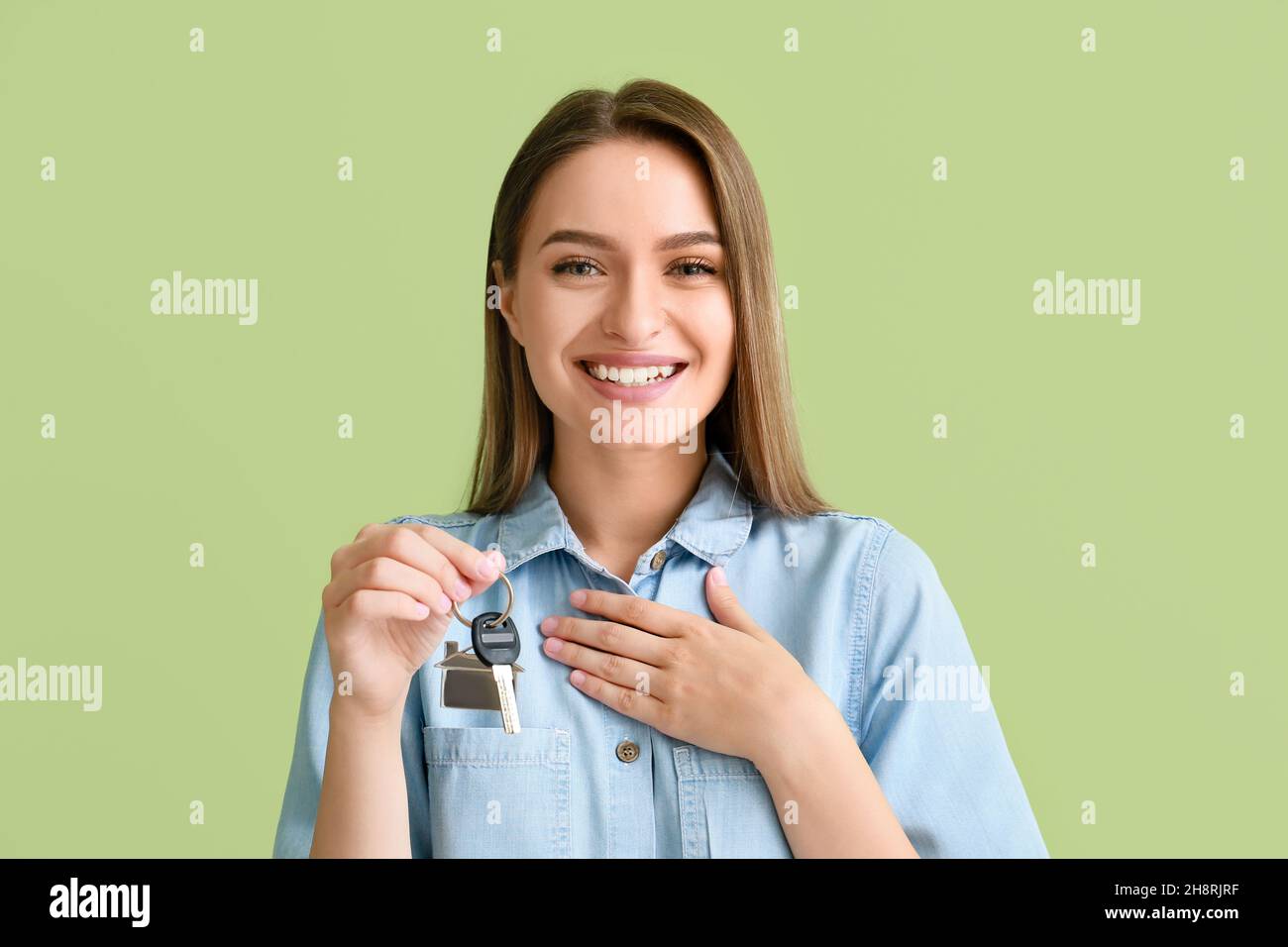 Happy young woman with key from house on green background Stock Photo ...