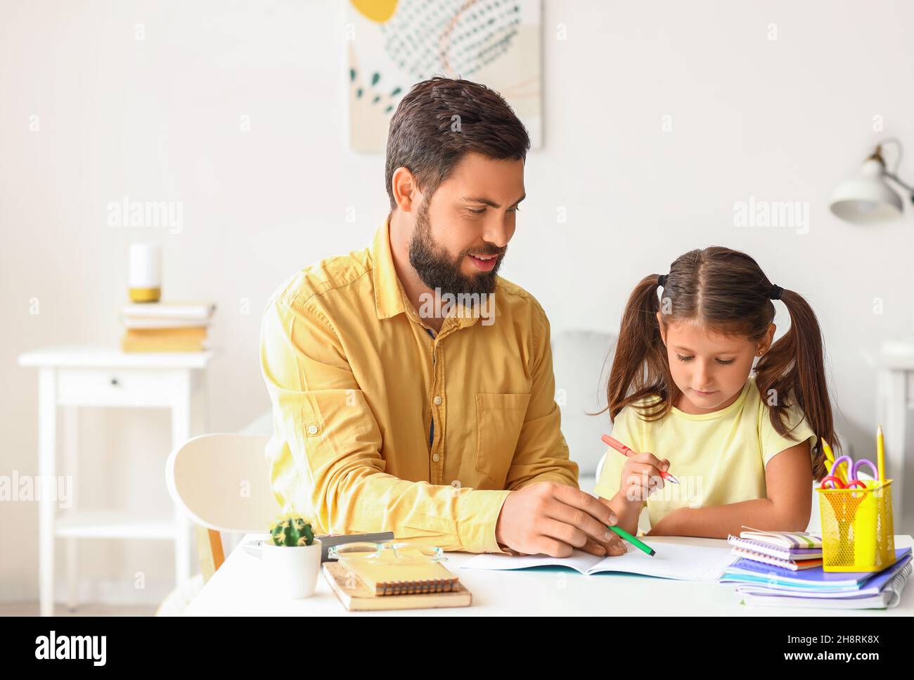 Man helping his little daughter to do lessons at home Stock Photo - Alamy