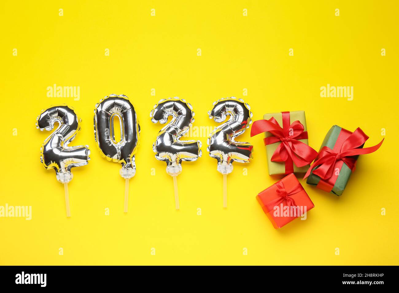 Figure 2022 made of silver balloons and gift boxes on yellow background ...
