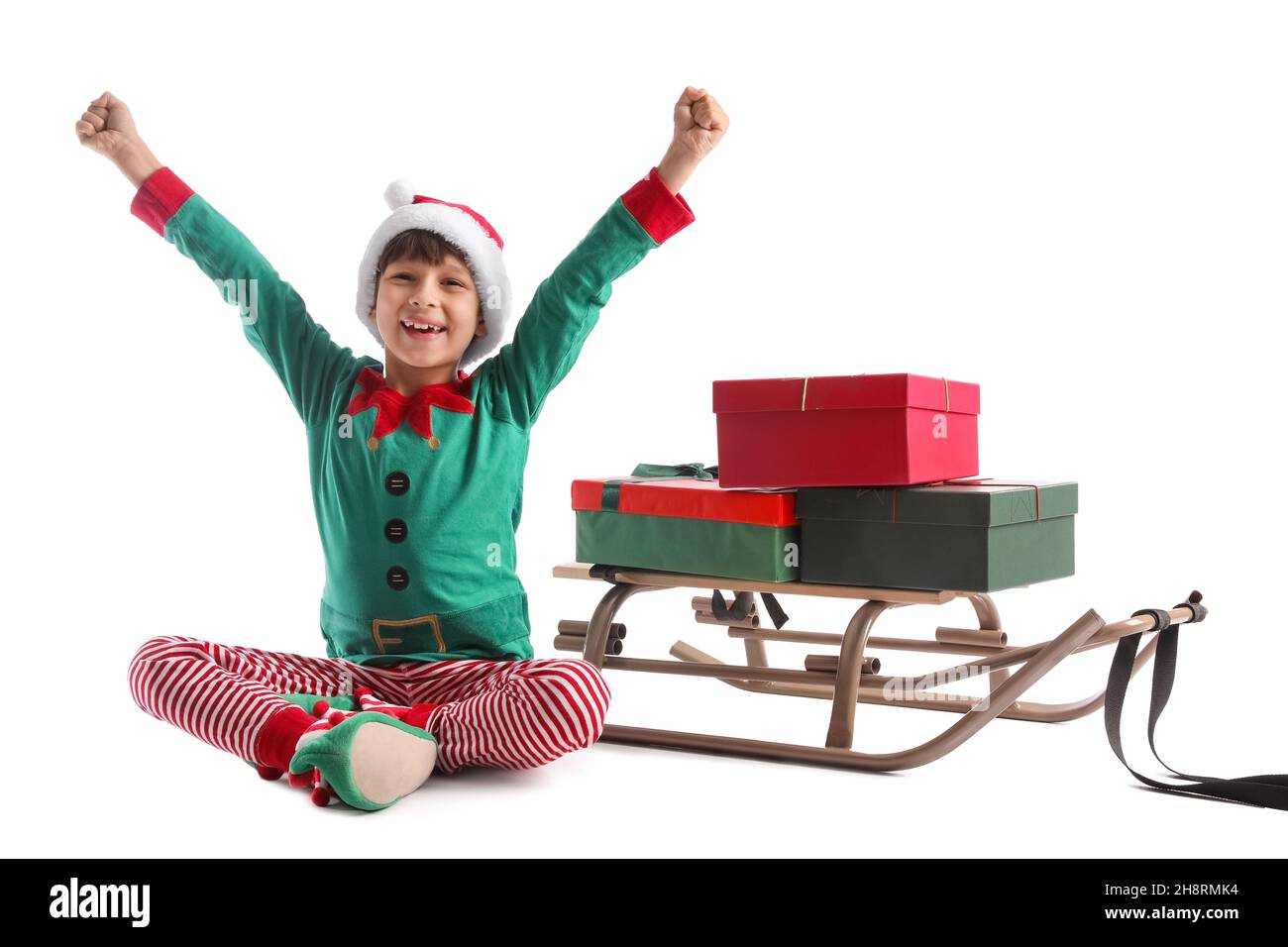 Little boy in elf costume, with sled and Christmas gifts on white ...