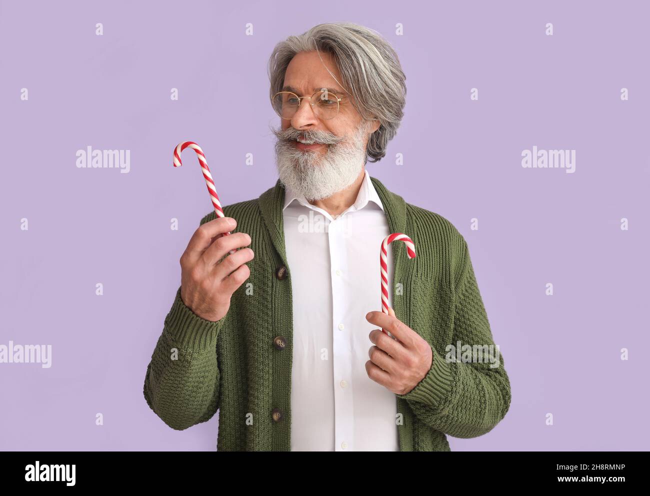 Senior man with sweet candy canes on color background Stock Photo - Alamy