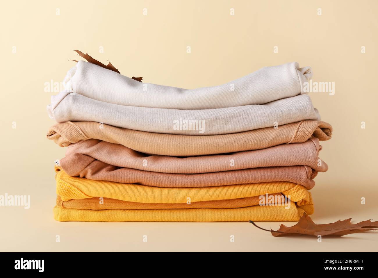 Stack of baby clothes and autumn leaves on color background Stock Photo ...