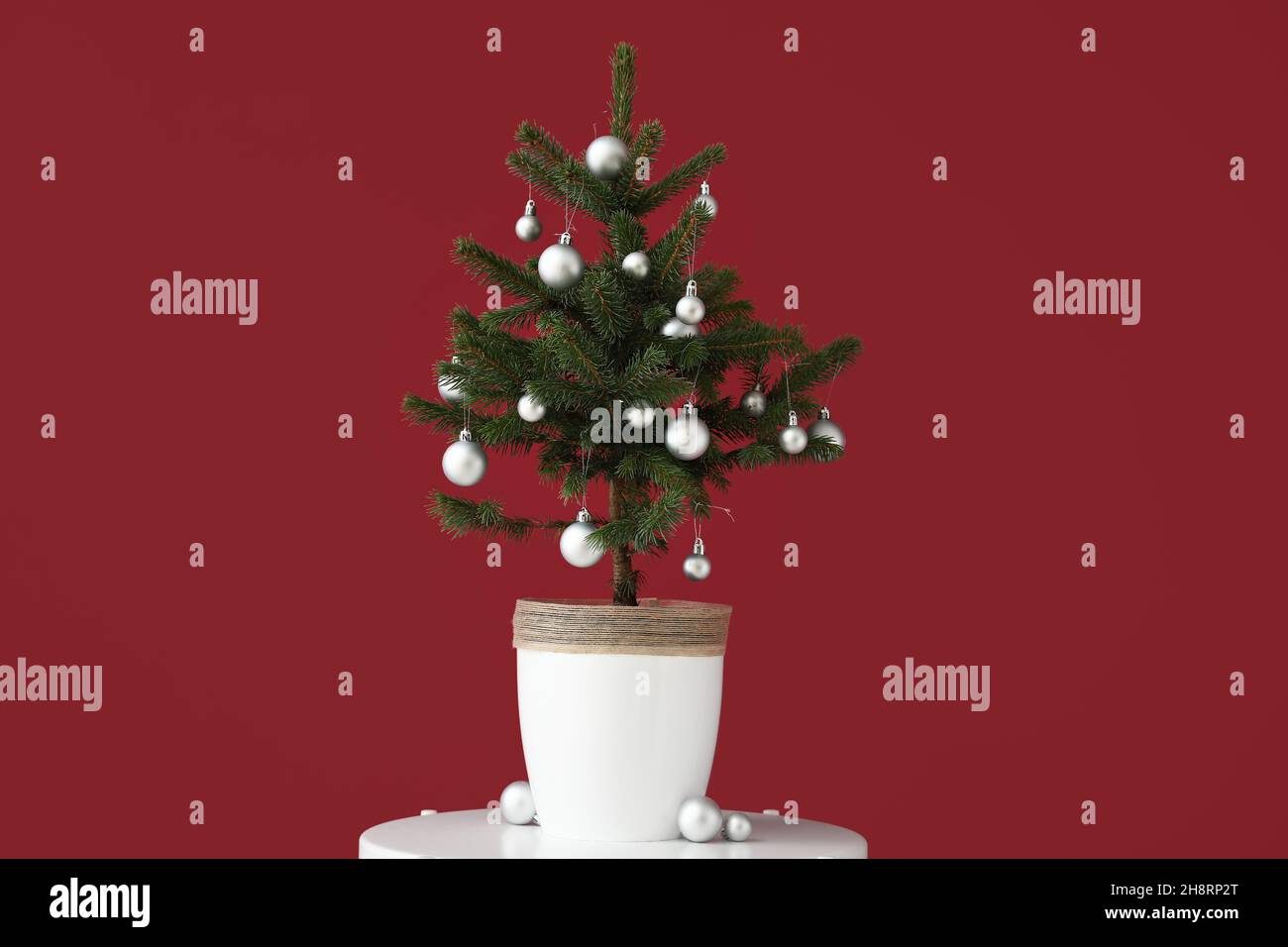 Beautiful decorated Christmas tree in pot on table near red wall Stock ...
