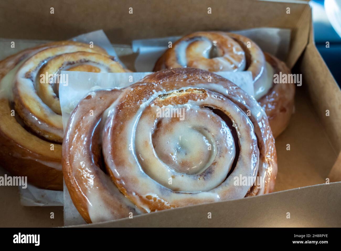 Angled view of an open pastry box filled with large, glazed homemade ...