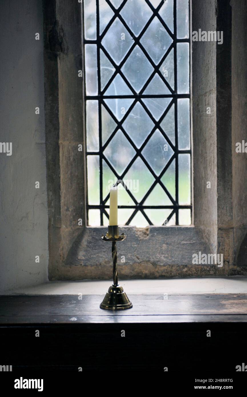 brass candlestick with unlit wax candle in leaded lights north norfolk ...
