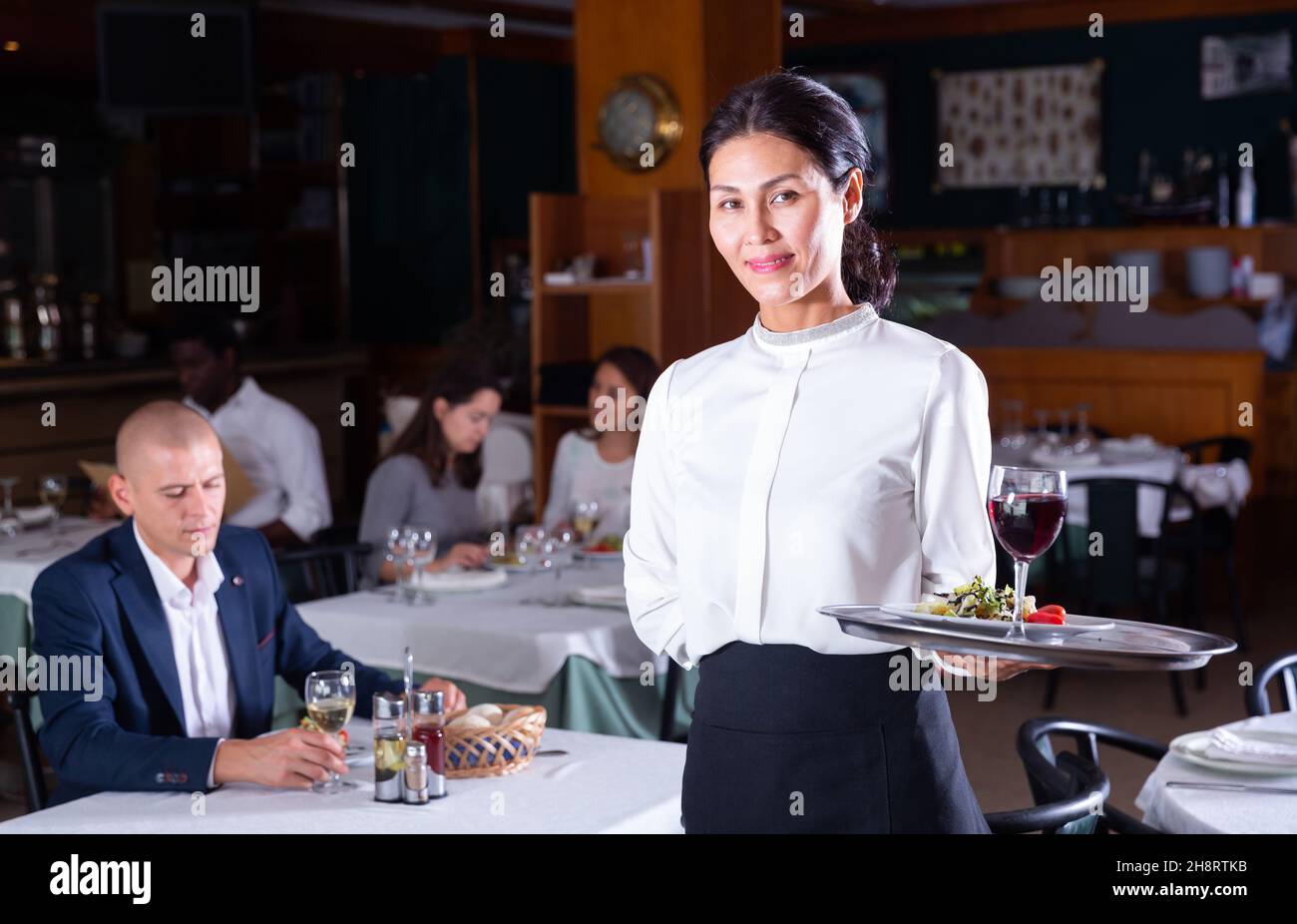Polite waitress with serving tray warmly welcoming in restaurant Stock ...