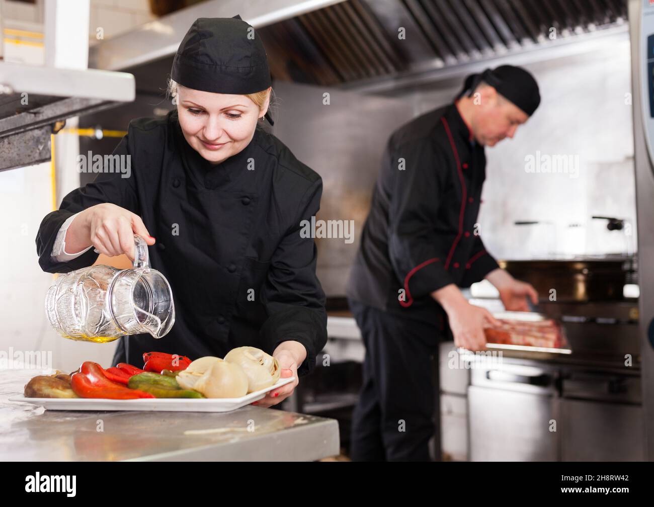 Female chef seasoning dish with oil Stock Photo - Alamy