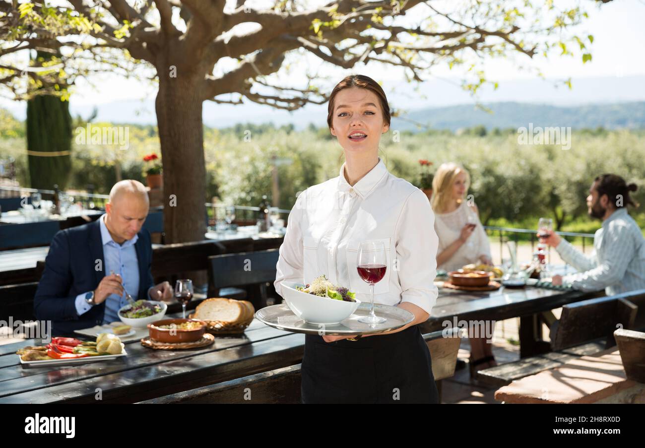 Waitress inviting guests on outdoor terrace Stock Photo - Alamy