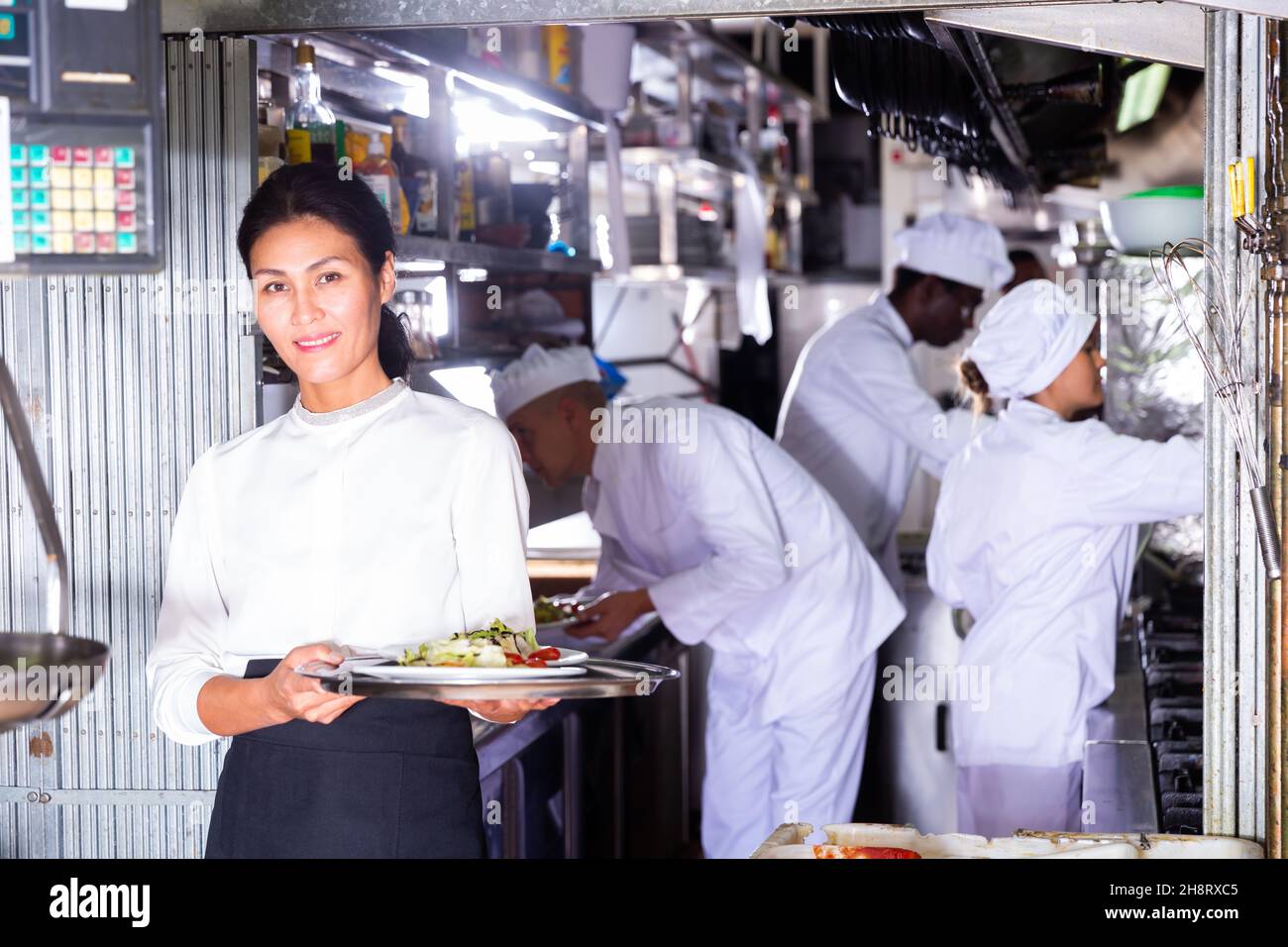Smiling waitress with ordered dishes in kitchen of restaurant Stock ...