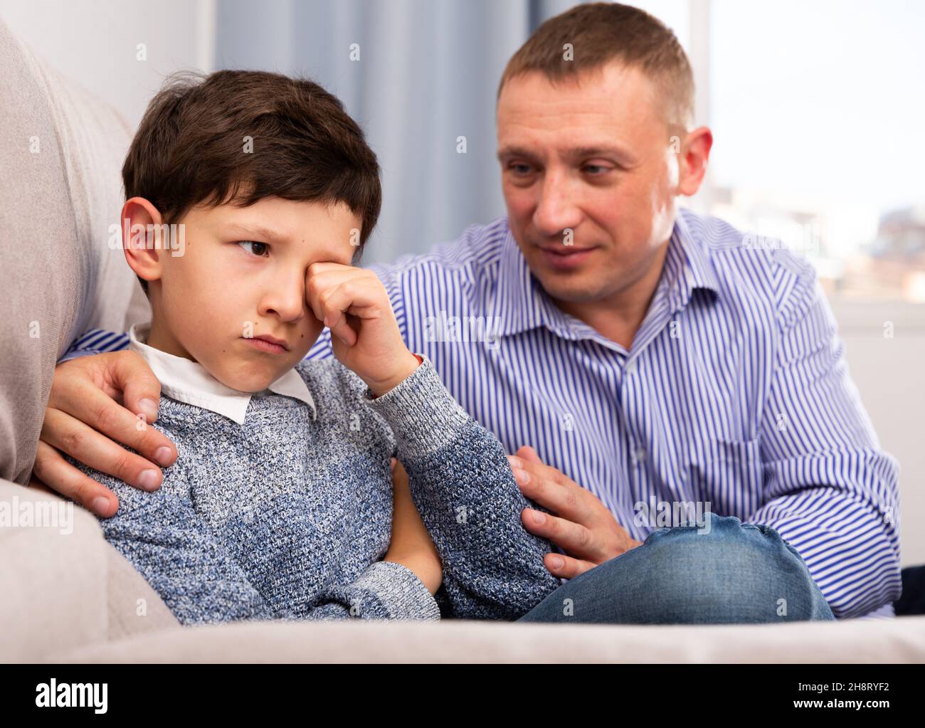 Young father consoling preteen son sitting at sofa after quarrel Stock ...