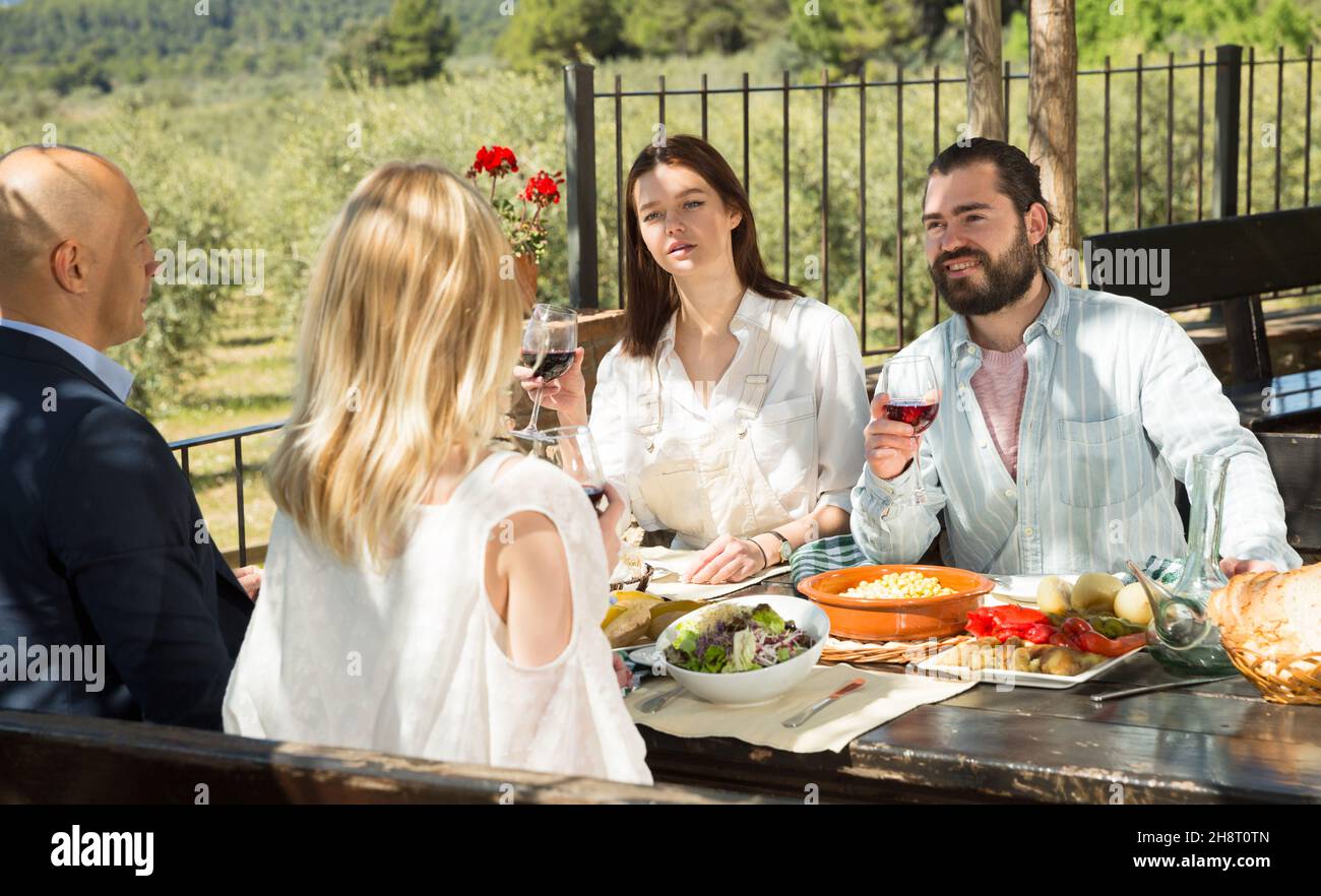 Positive middle class people enjoying food and wine on the open-air ...