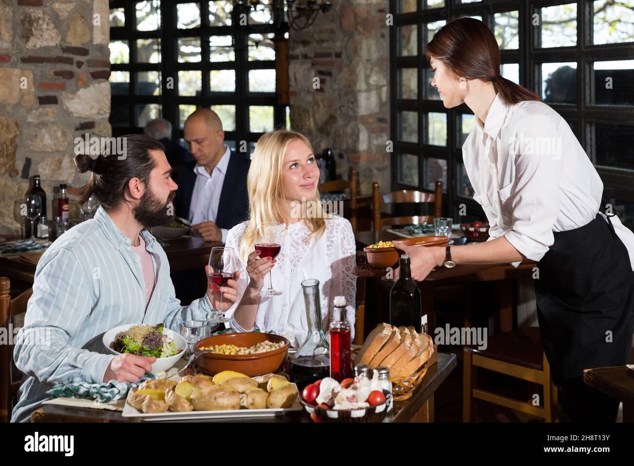 Waitress bringing dishes to guests Stock Photo - Alamy