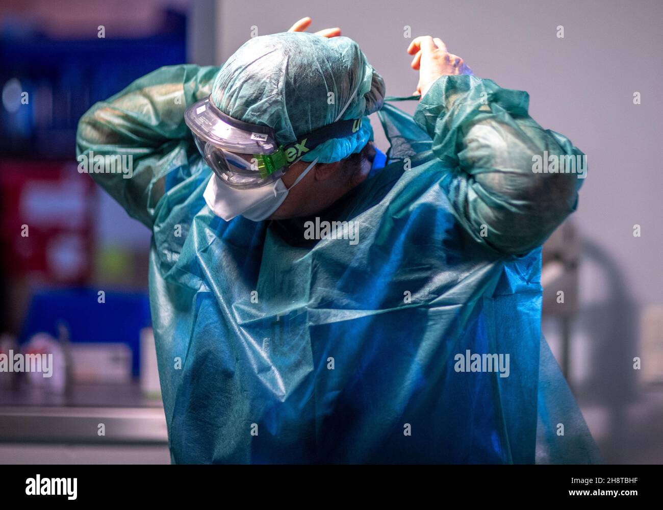 Rostock, Germany. 30th Nov, 2021. A nurse puts on her protective ...