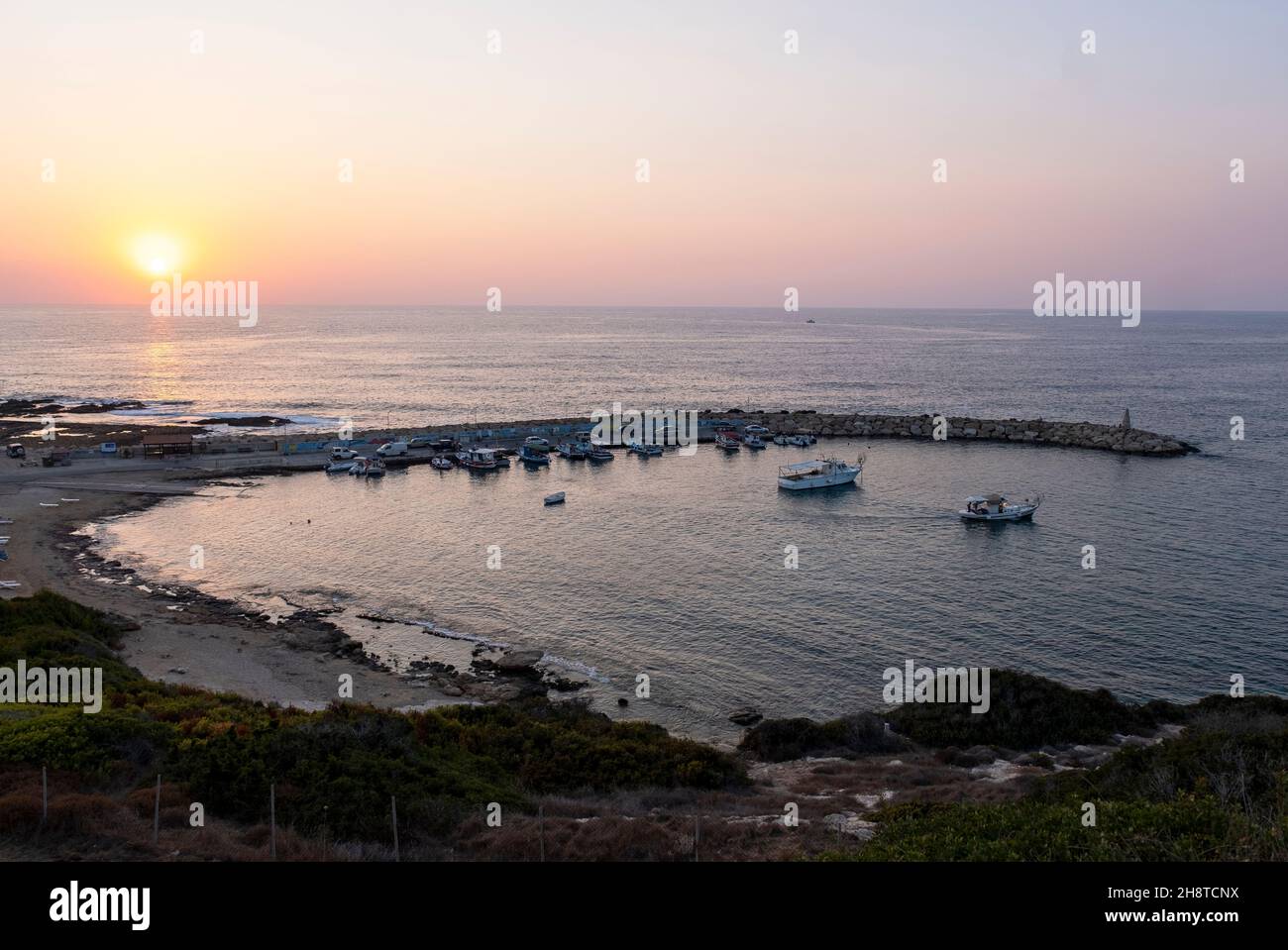 The sun sets over the small fishing harbour of Agios Georgios (St ...