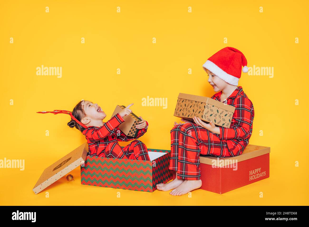 Girl sitting in gift box next to boy sitting on box Stock Photo - Alamy