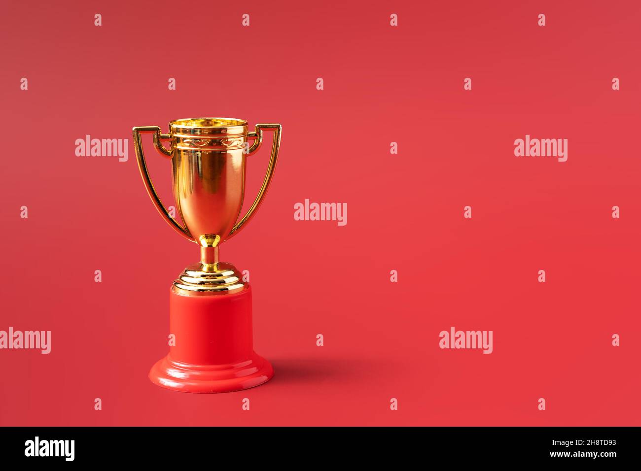 Gold color victory cup on red background Stock Photo - Alamy