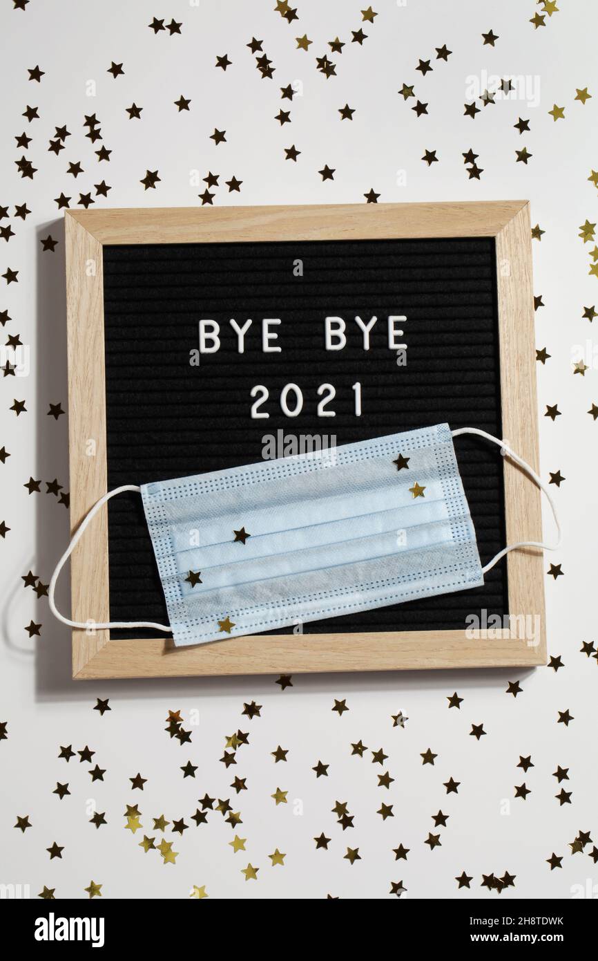 black letter board with text BYE BYE 2021 with small stars and mask on ...