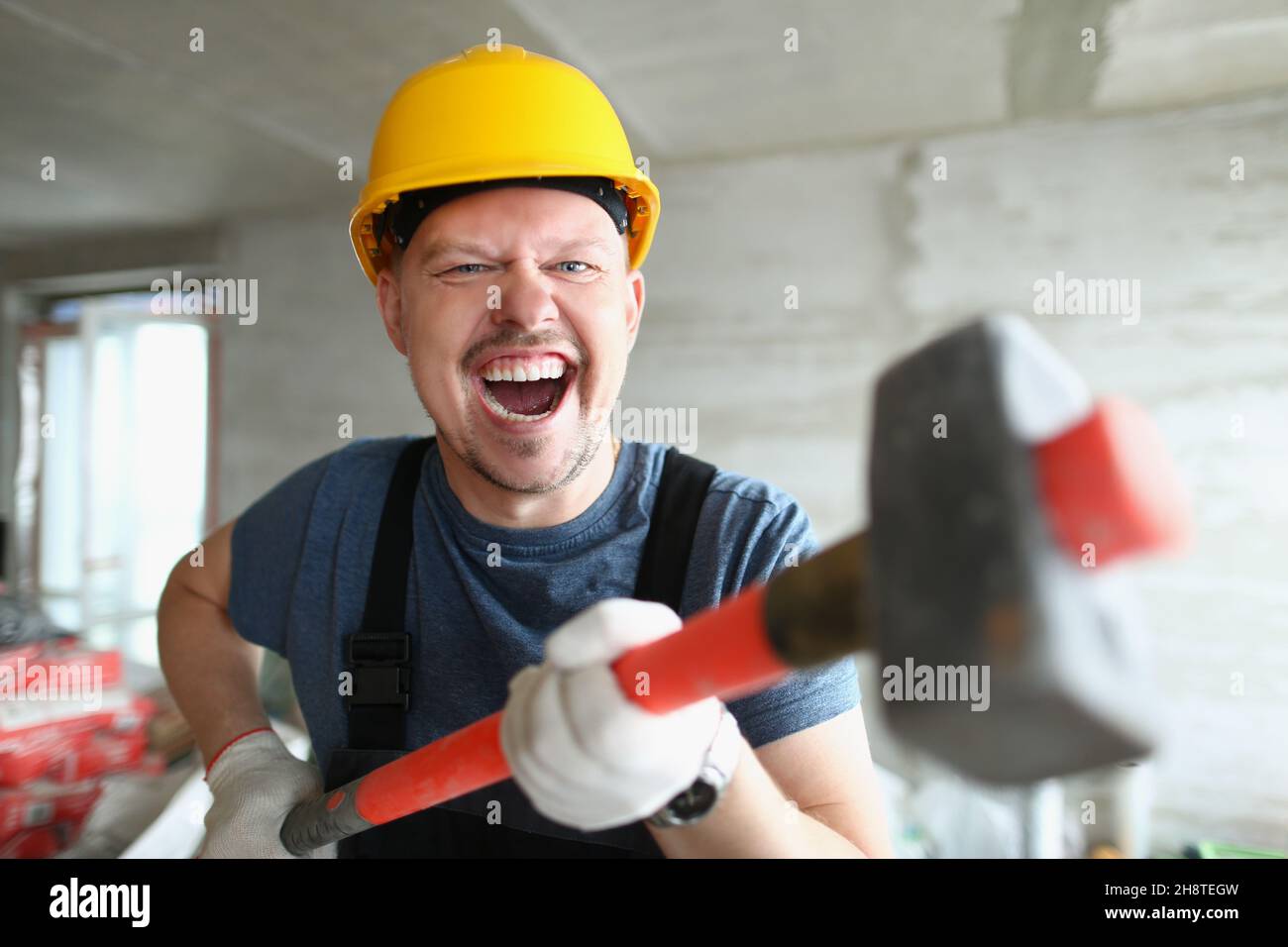 Builder man with a long hammer in his hands Stock Photo - Alamy