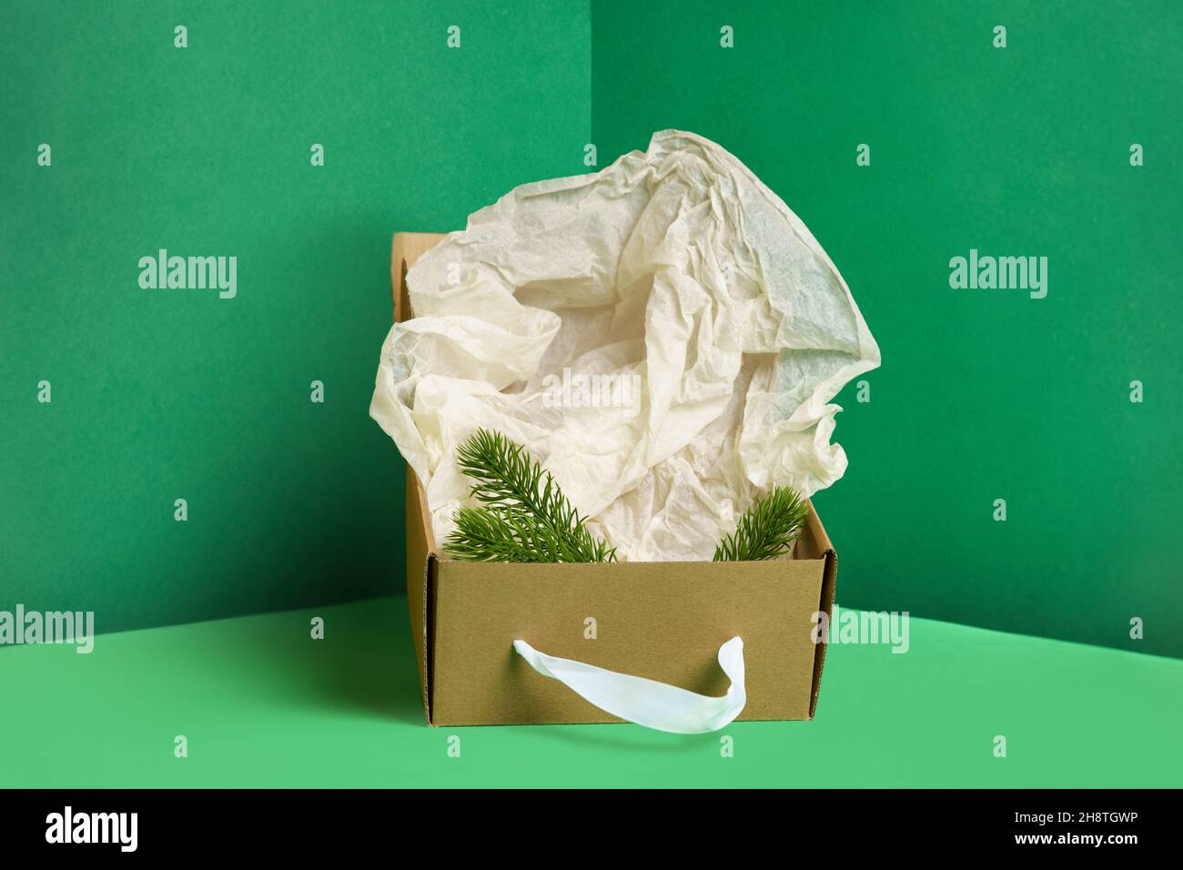 Craft box with wrapping paper inside, branch of green fir tree in green ...