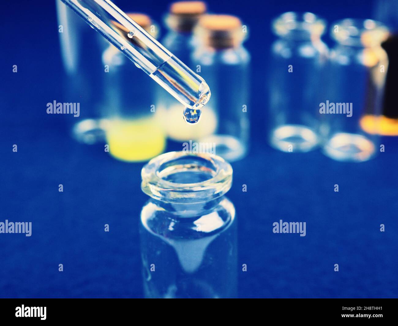 drop of liquid from a pipette into a medical bottle, research concept ...