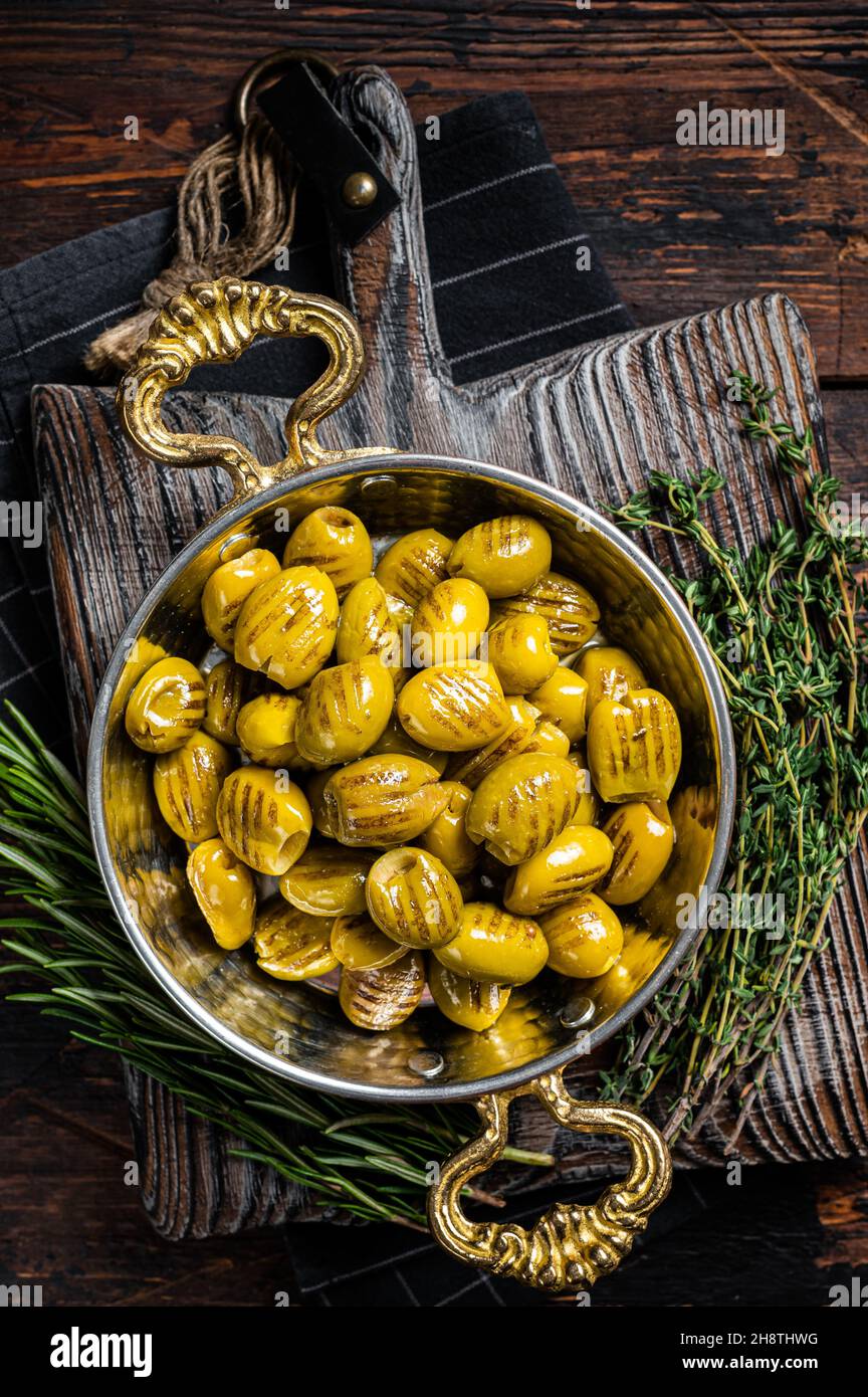 Turkish Grilled olives with olive oil and herbs in pan. Wooden ...