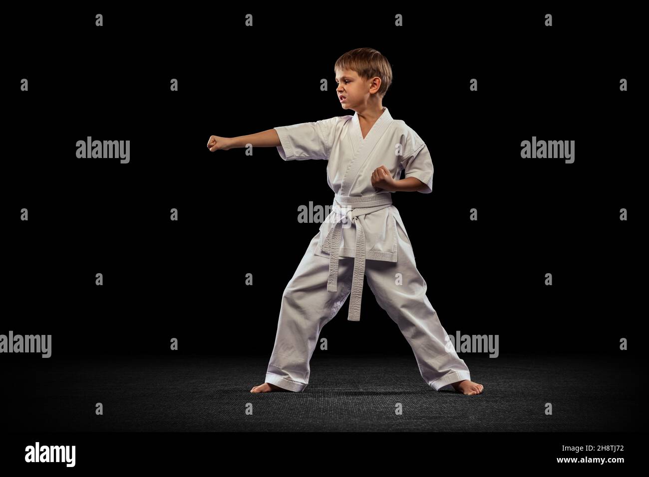 Full-length portrait of little boy, sportsman standing in front stance ...
