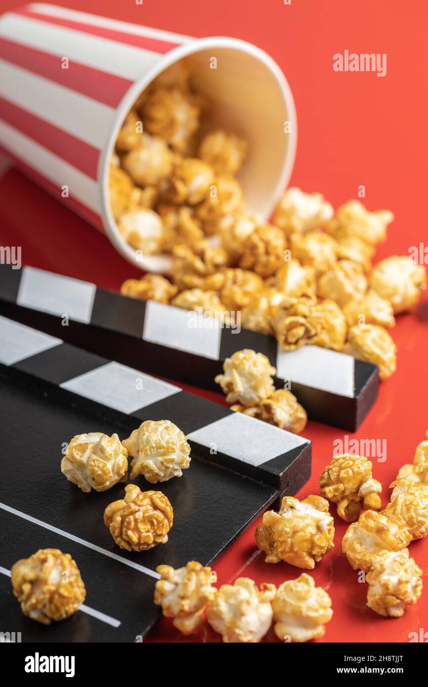 Sweet caramel popcorn and clapper board on red background Stock Photo ...