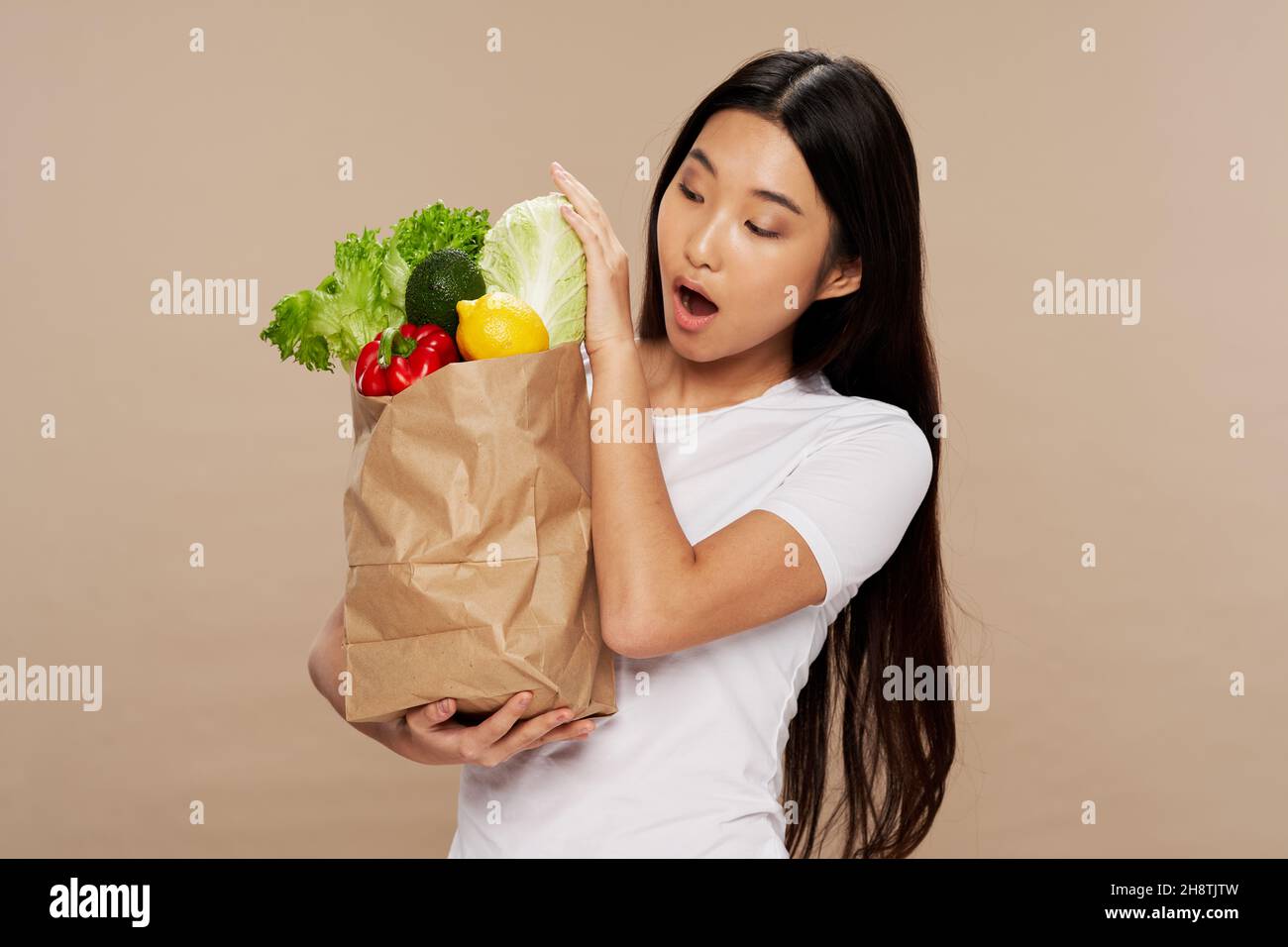 woman with a package of groceries healthy food snacks beige background ...
