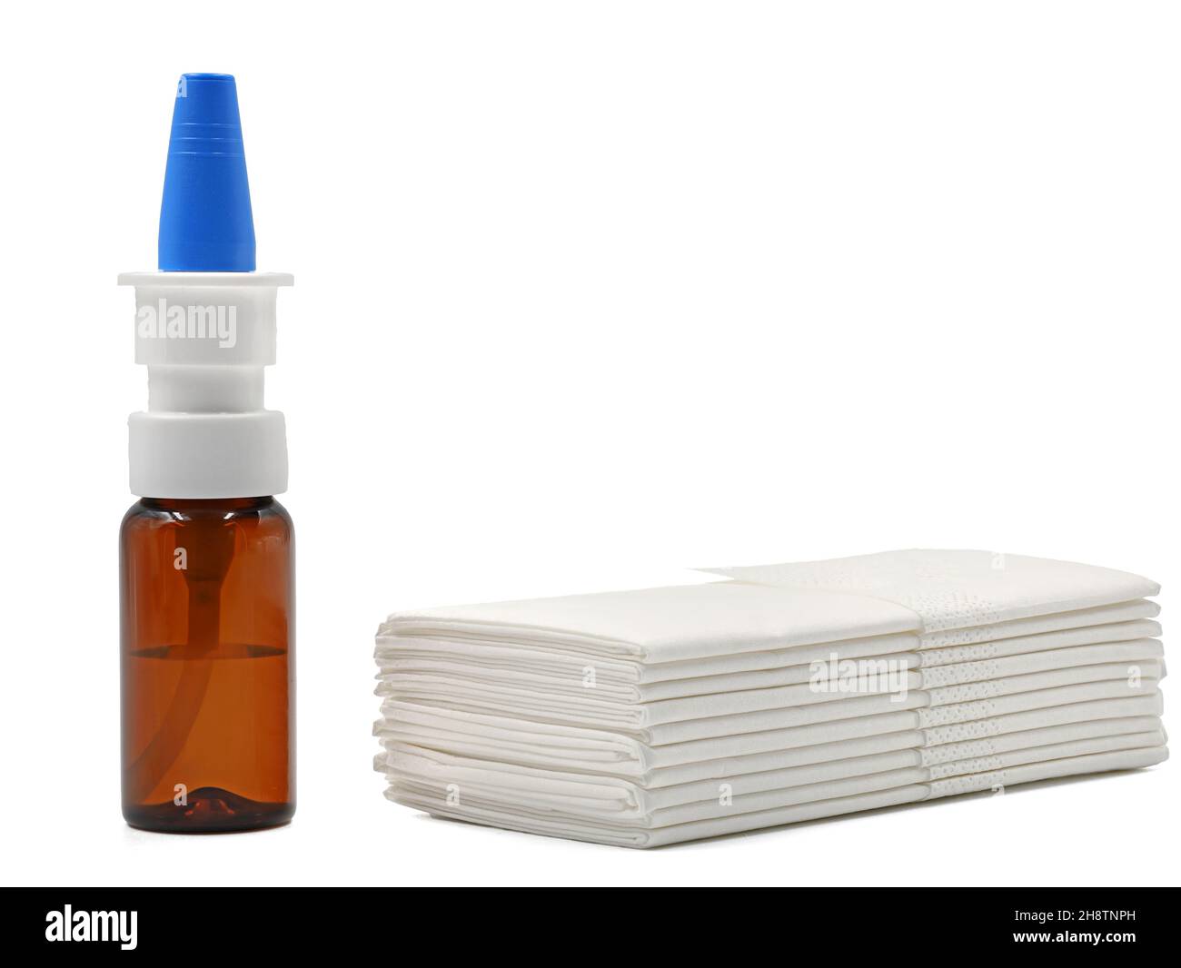 Nasal spray and a stack of paper tissues on a white background with ...